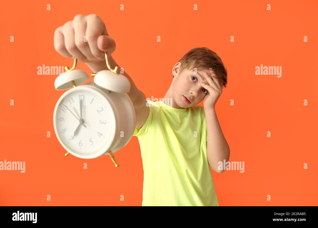 Emotional little boy with alarm clock on color background Stock Photo ...