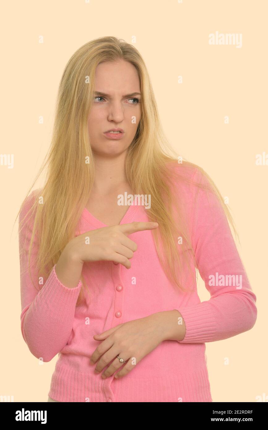 Studio shot of young beautiful teenage girl pointing finger and looking ...