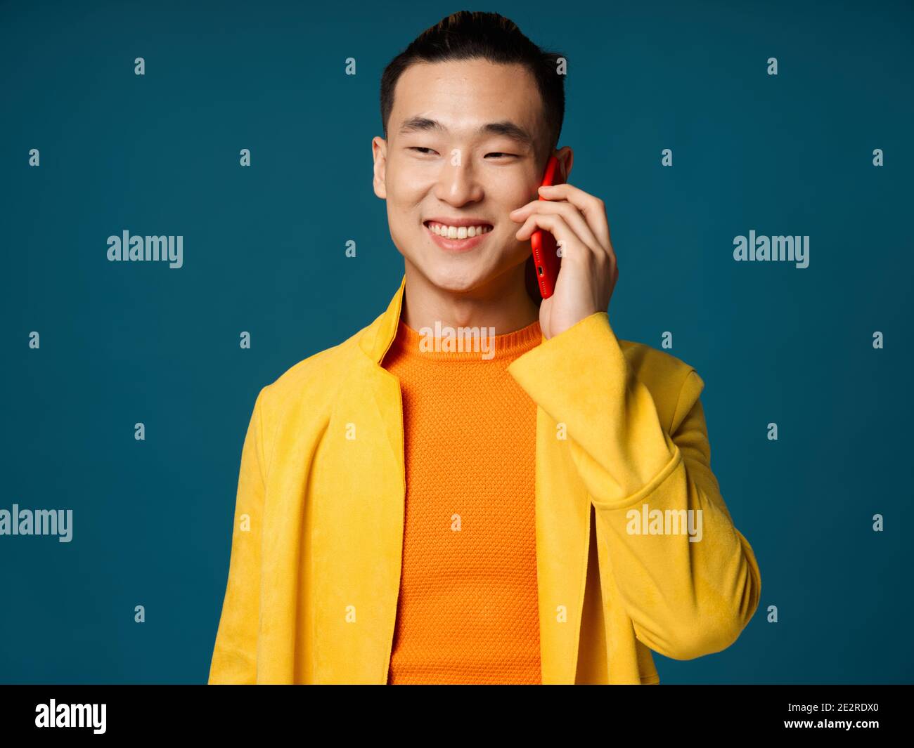 happy asian man talking on the phone on blue background Stock Photo - Alamy