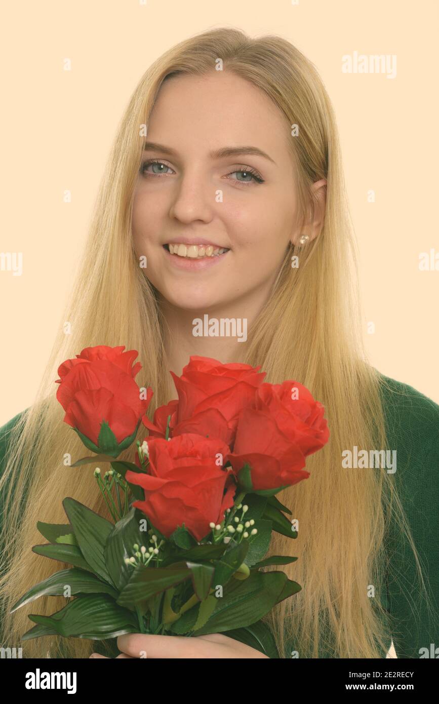 Face of young happy teenage girl smiling while holding red roses ready ...