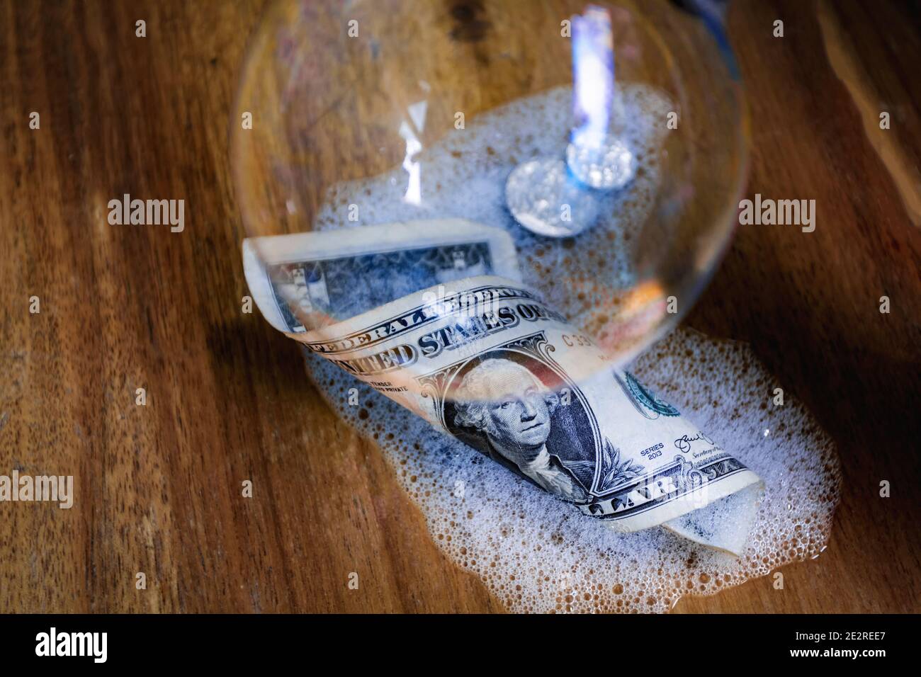 A big bubble on a dollar bill and two coins that are surrounded by foam ...