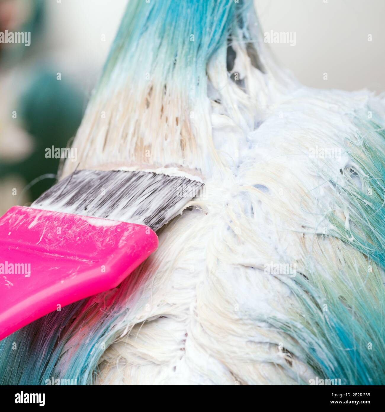 Close-up of stylist using pink brush while applying paint to female ...