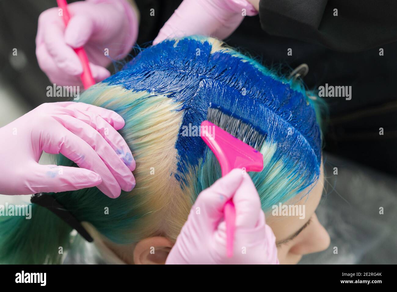 Hairdressers using pink brush while applying blue paint to female ...