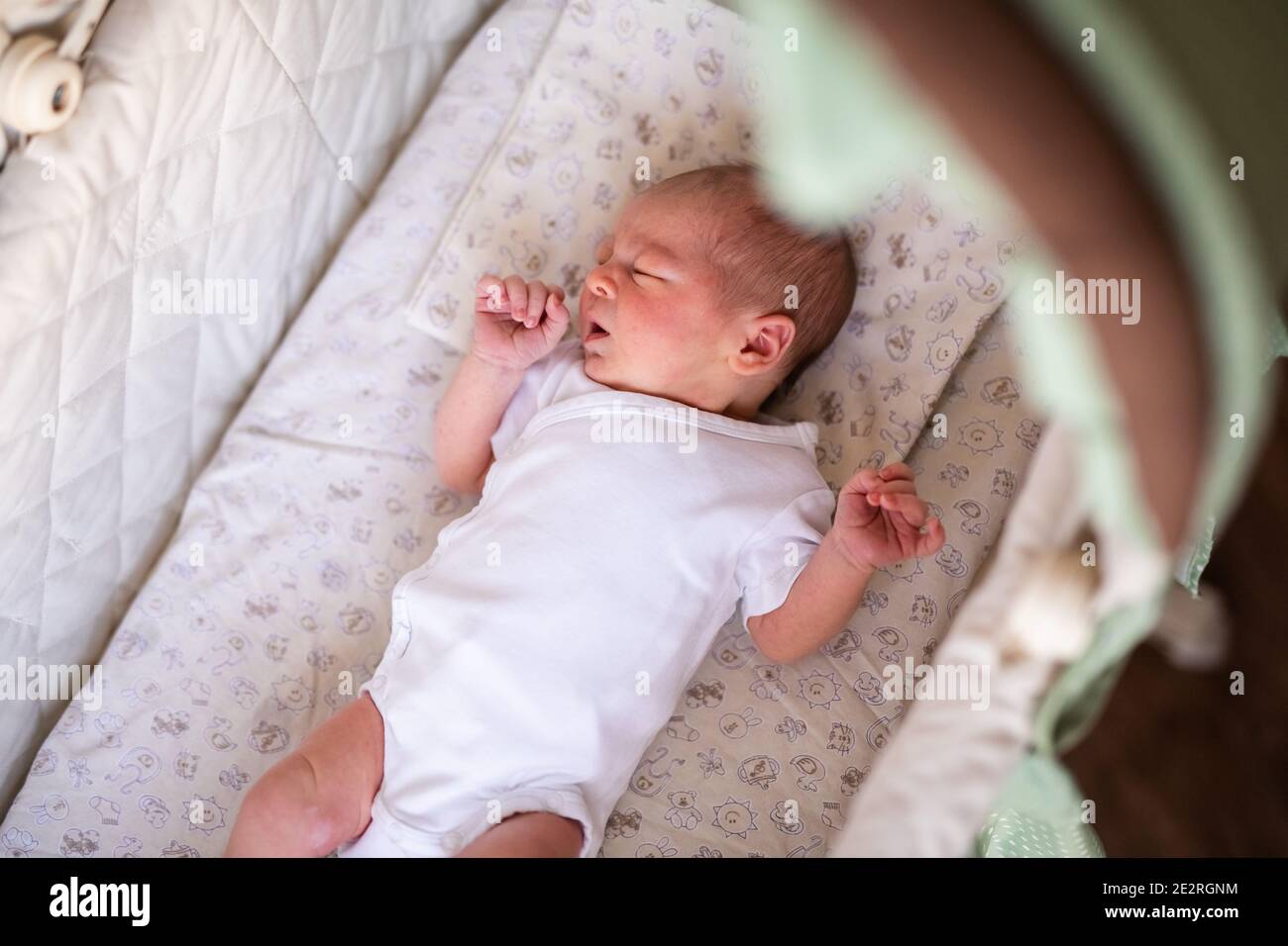 Newborn baby boy in bed. New born child in white bodykit lying in light ...