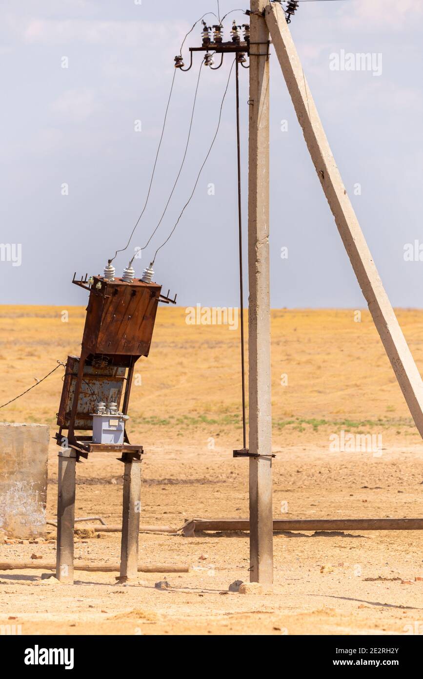 Transformer station near a pillar in steppe. Rural power lines ...