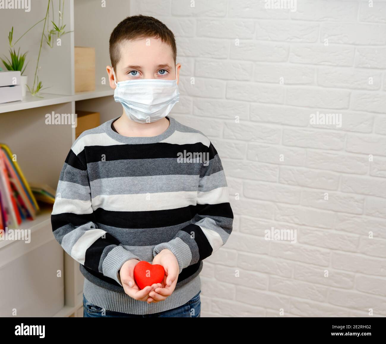 Desperate child boy holding red toy heart in hands. Medical concept ...