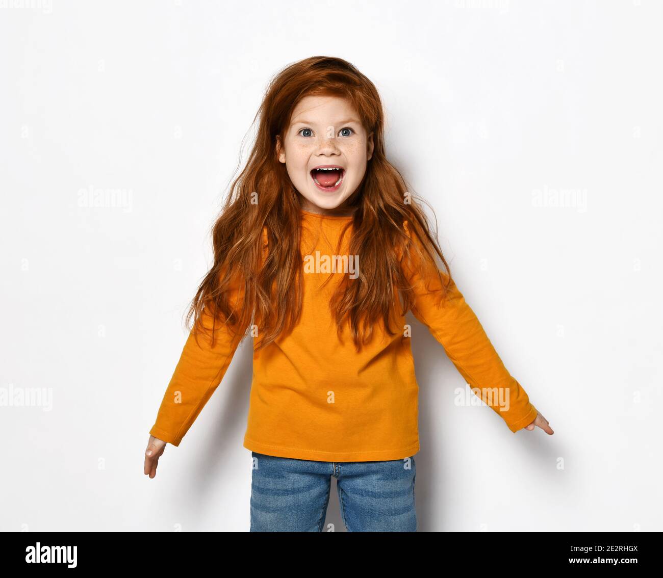 Excited shocked screaming loudly red-haired kid girl in orange ...