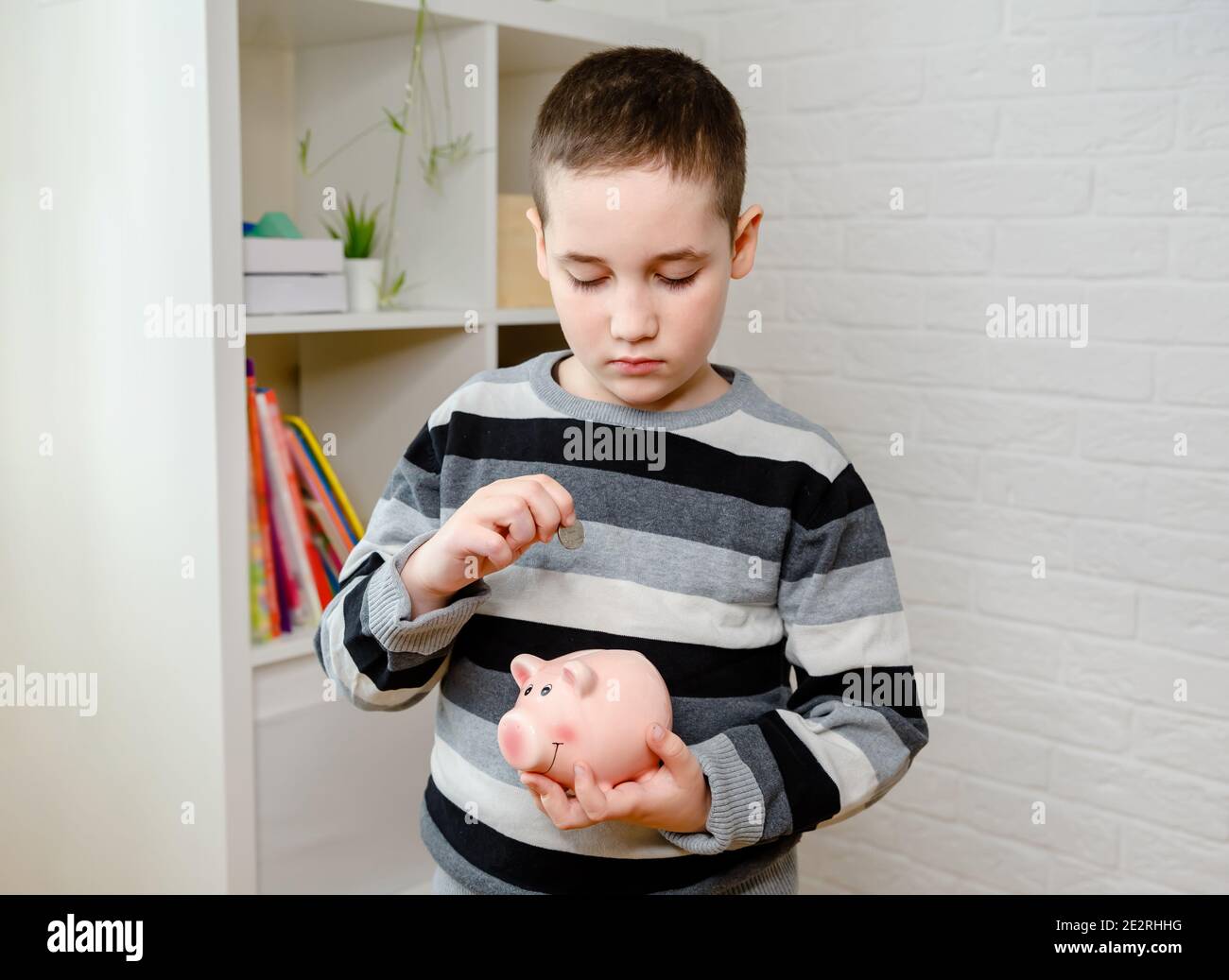 Boy putting coins into piggy bank. Learning financial responsibility ...