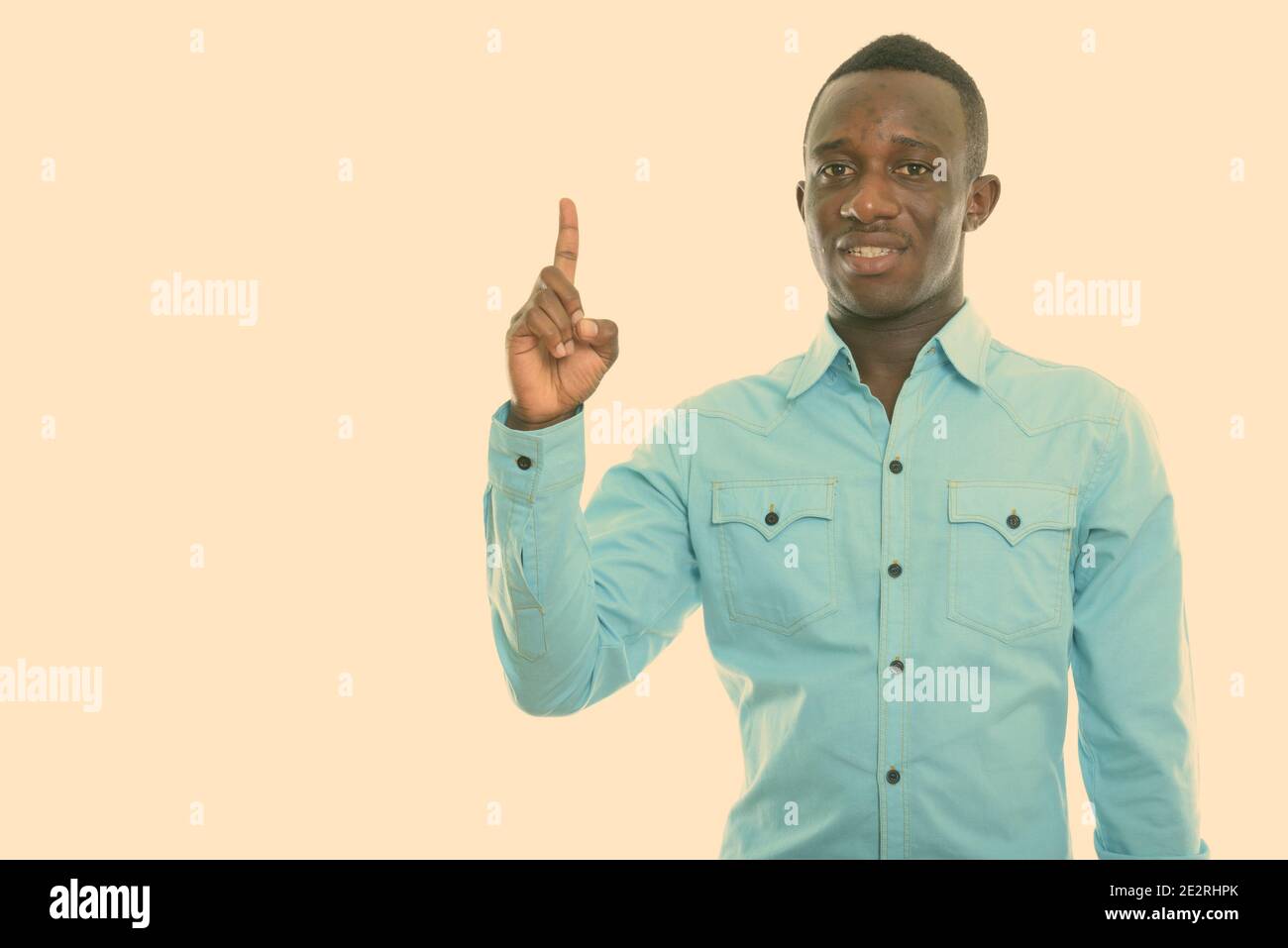 Studio shot of young happy black African man smiling while pointing ...