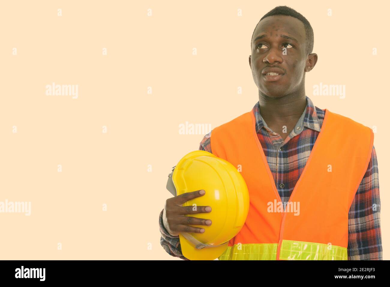 Studio shot of young black African man construction worker thinking ...