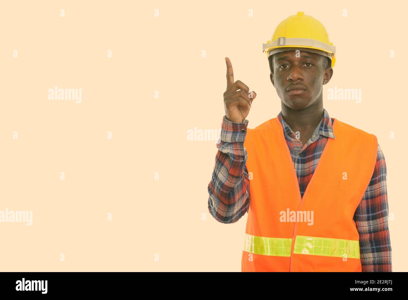 Studio shot of young black African man construction worker pointing ...
