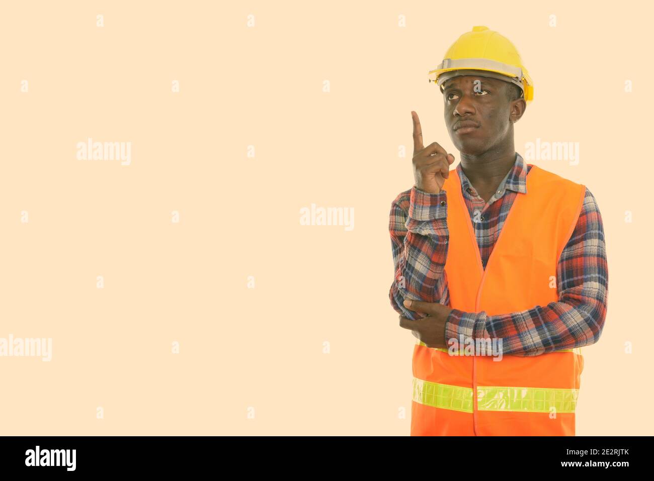 Studio shot of young black African man construction worker thinking ...