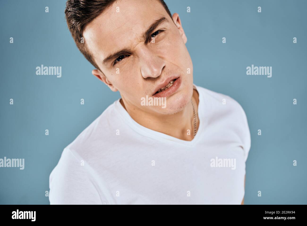 emotional displeased man cropped view white t-shirt blue background ...