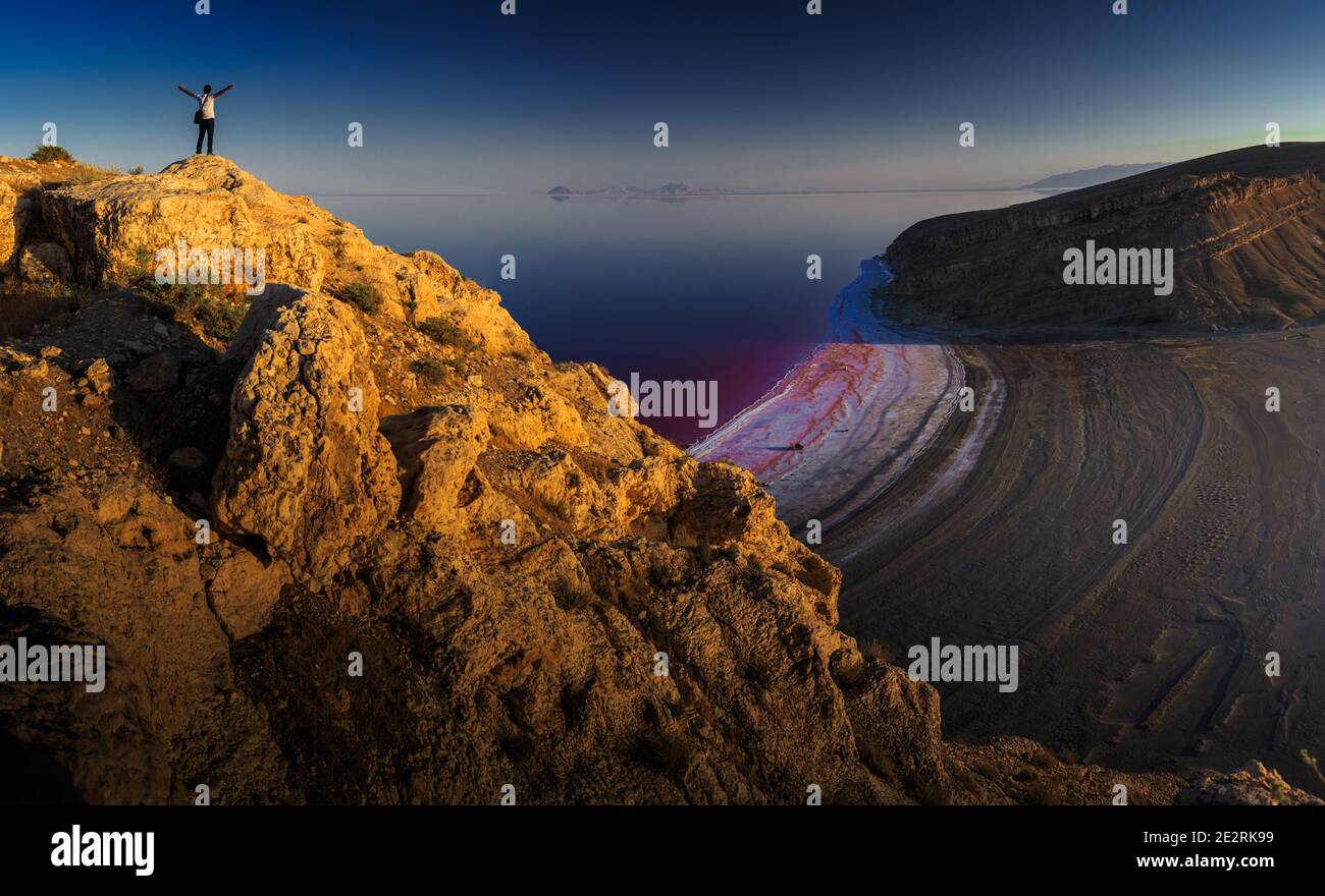 Back view of a man on the peak of a rocky mountain with open arms ...