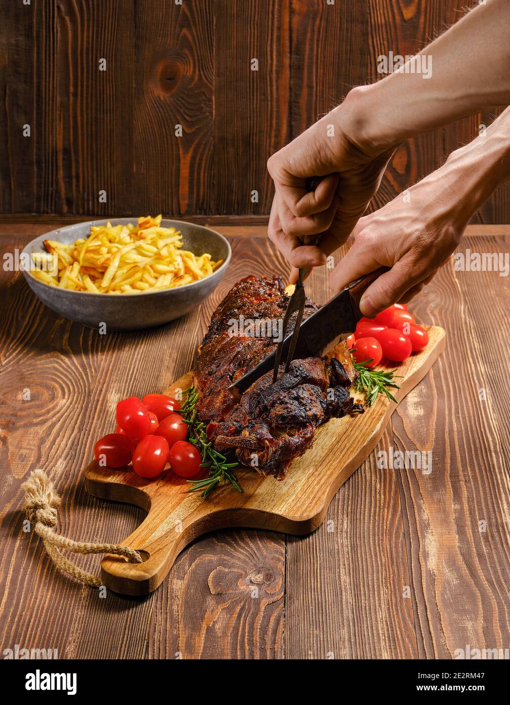 Cutting with knife baked lamb leg Stock Photo - Alamy
