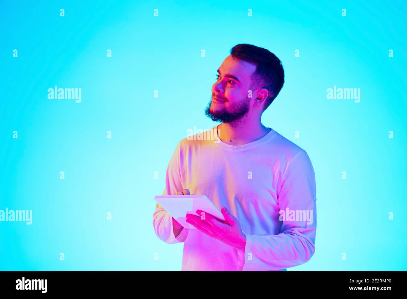 Scrolling tablet. Caucasian man's portrait with device on blue studio ...