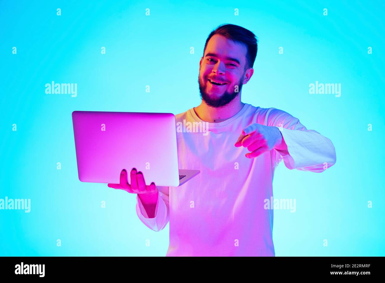 Using laptop. Caucasian man's portrait with device on blue studio ...