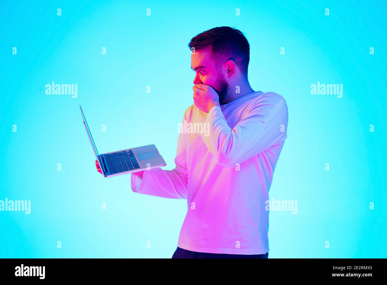 Using laptop. Caucasian man's portrait with device on blue studio ...
