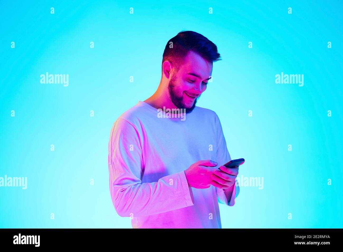 Using cellphone. Caucasian man's portrait with device on blue studio ...