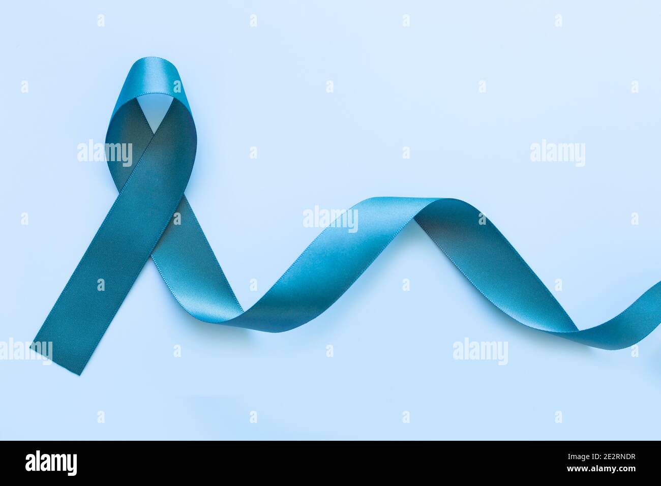 Teal color ribbon bow on blue isolated background with copy space ...
