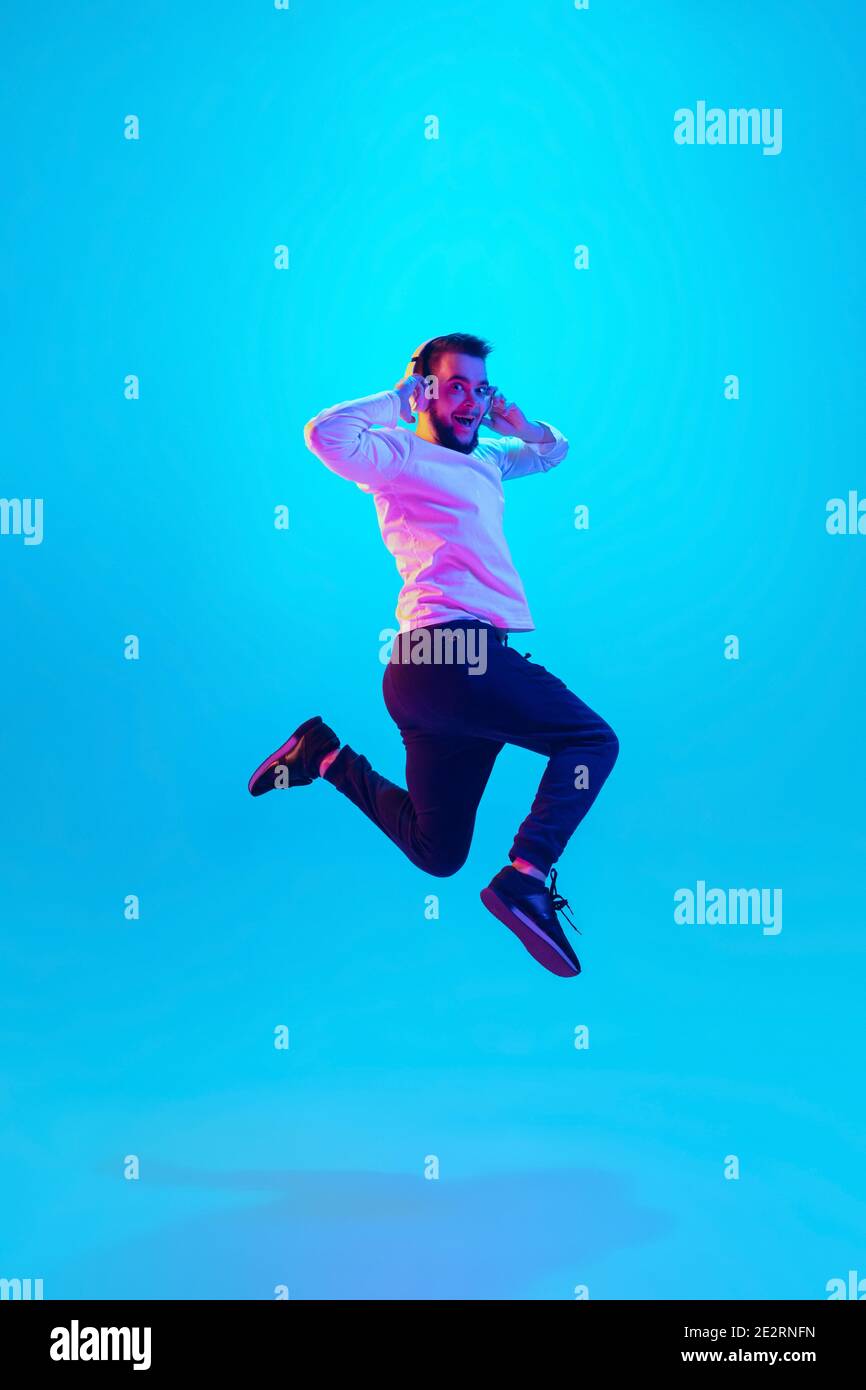 Jumping high. Caucasian man's portrait isolated on blue studio ...