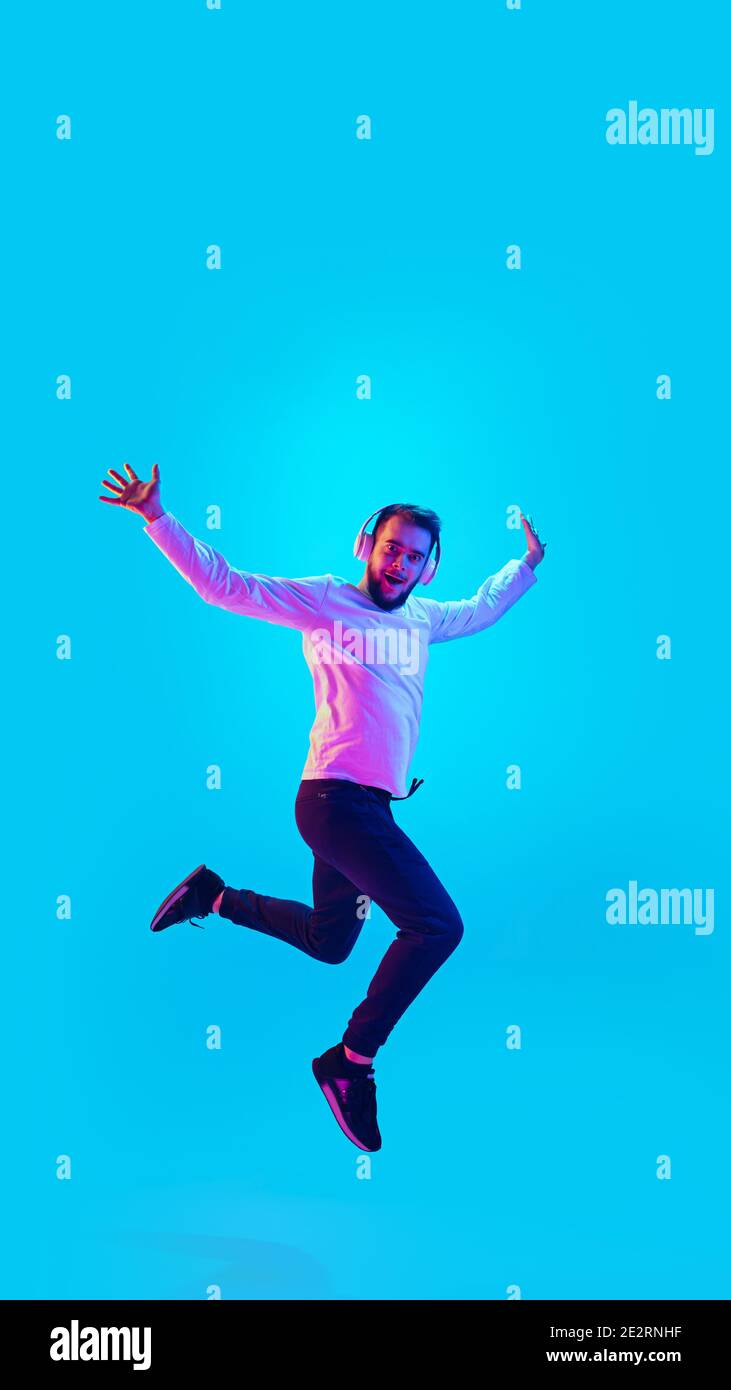Jumping high. Caucasian man's portrait isolated on blue studio ...