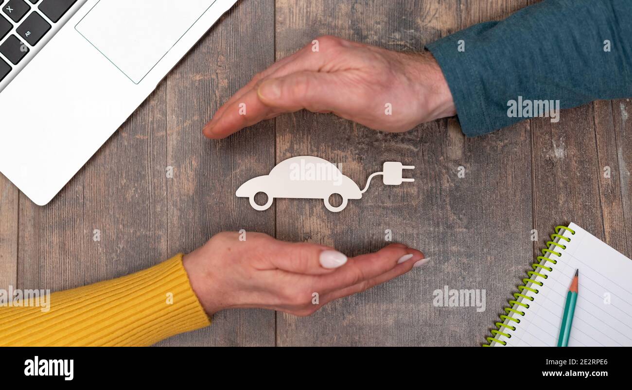 Hands protecting a paper electric car; Concept of eco friendly car ...