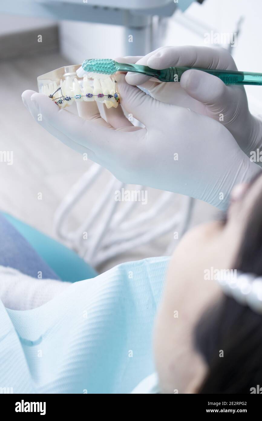Vertical closeup of a doctor showing how to correctly brush teeth on a ...