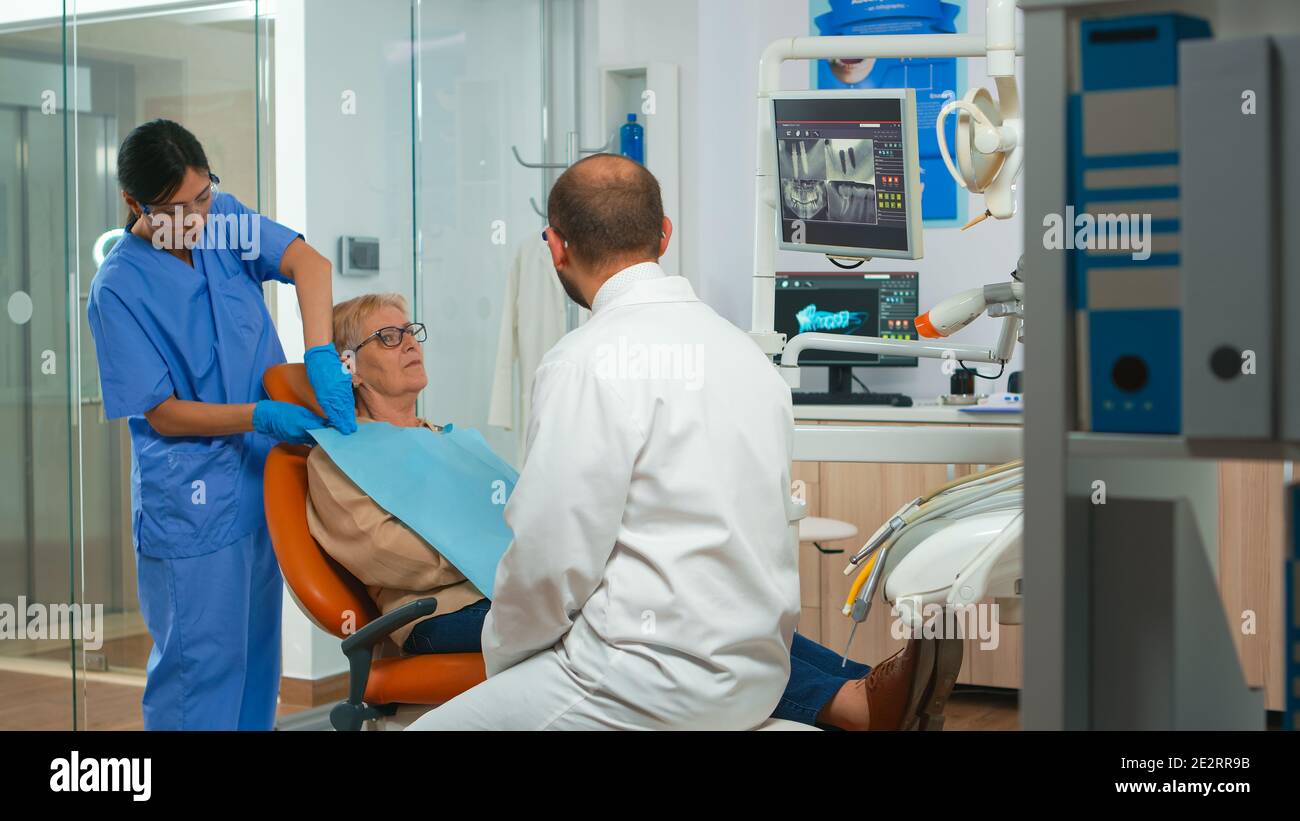 Stomatologist pointing on digital screen explaining x-ray to elderly ...