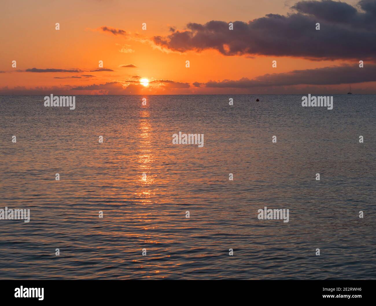 Sunrise with the red orange sun raising up from the sea with dark ...