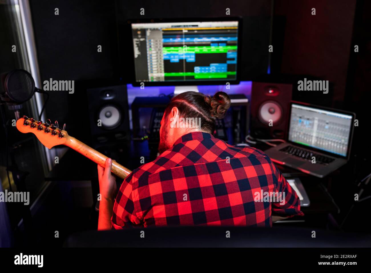 Hipster man playing guitar and sining his new song in stereo studio to ...