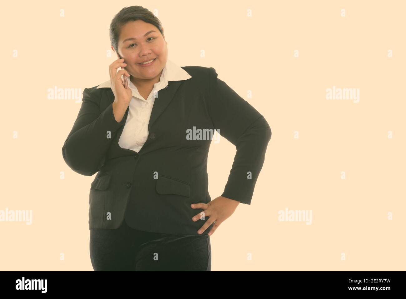 Studio shot of young happy fat Asian businesswoman smiling while ...