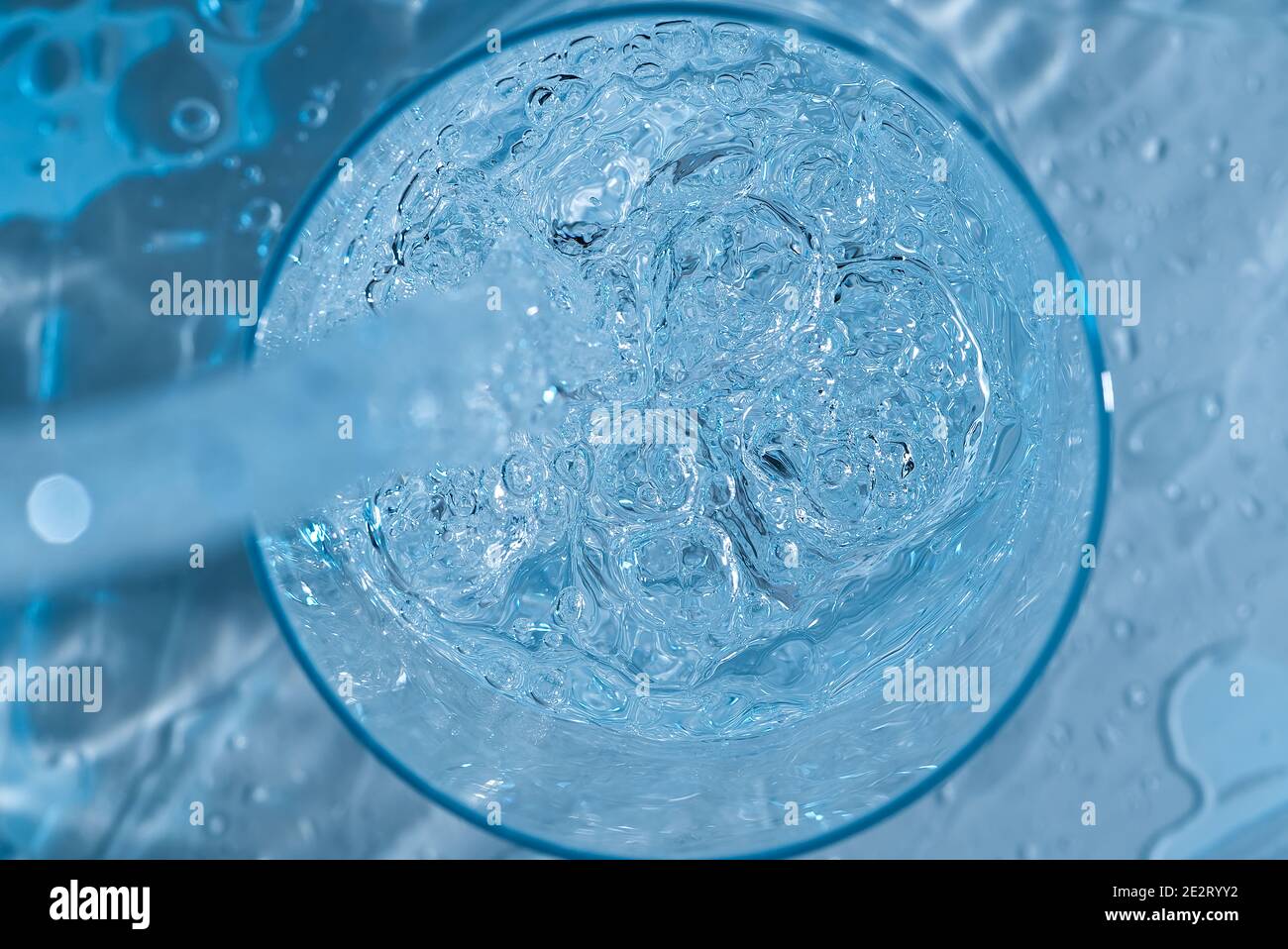 Pouring clean drinking water from blue plastic bottle into glass on ...