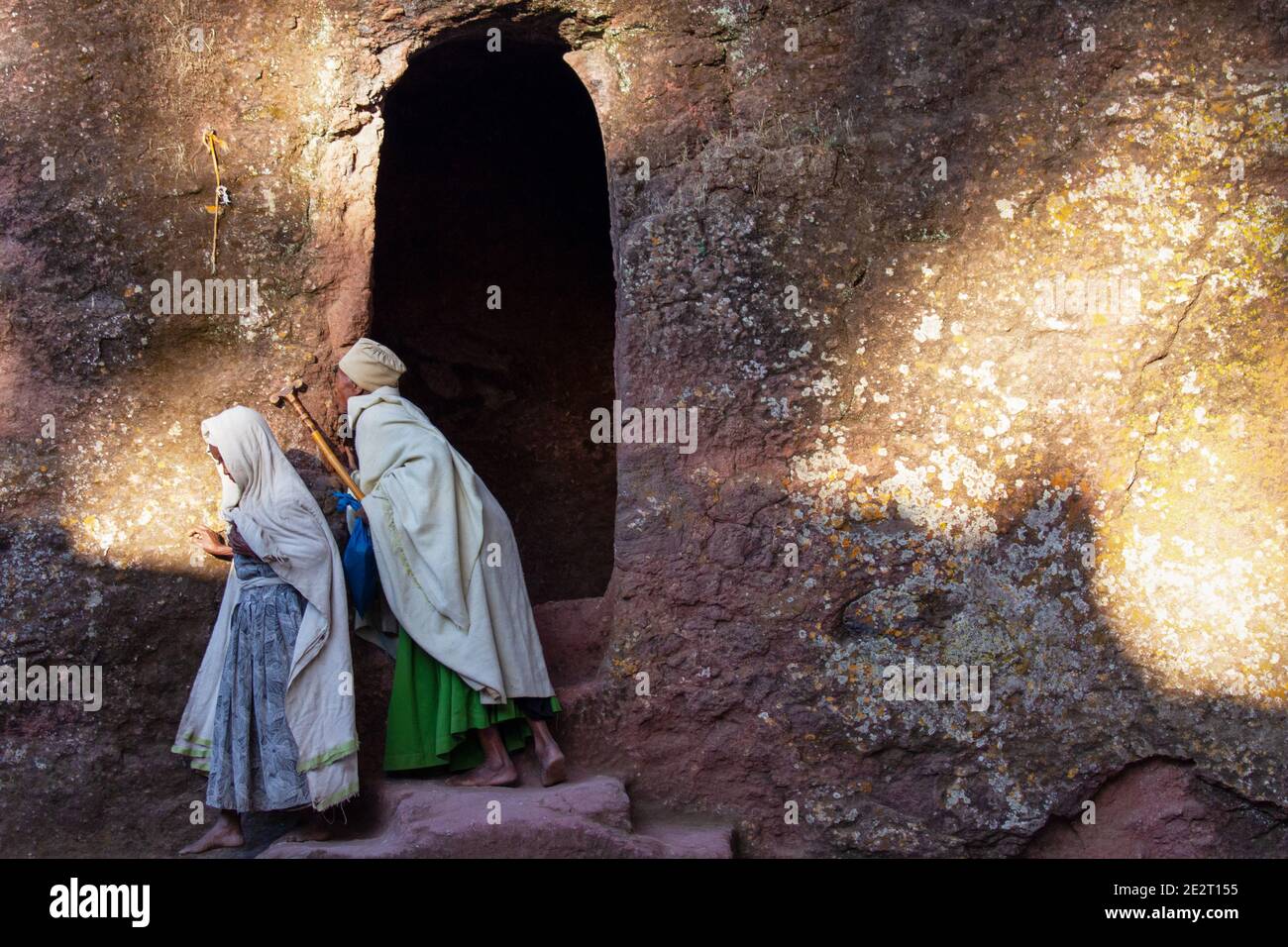 Deeply religious Pilgrims praying and kissing wall of Rock-Hewn Church ...