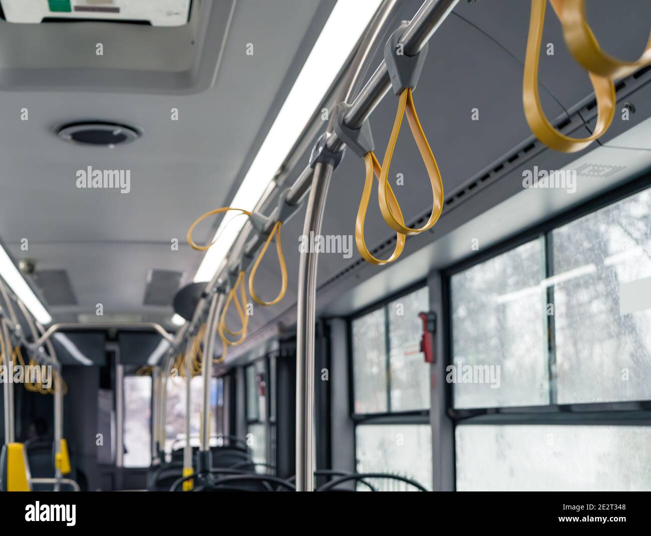 Interior of a empty bus with many hand holders or grips on the handle ...