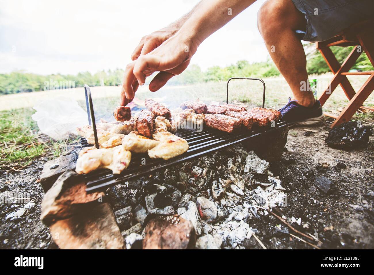 prepares a meat on the barbecue grill, unrecognizable man making ...