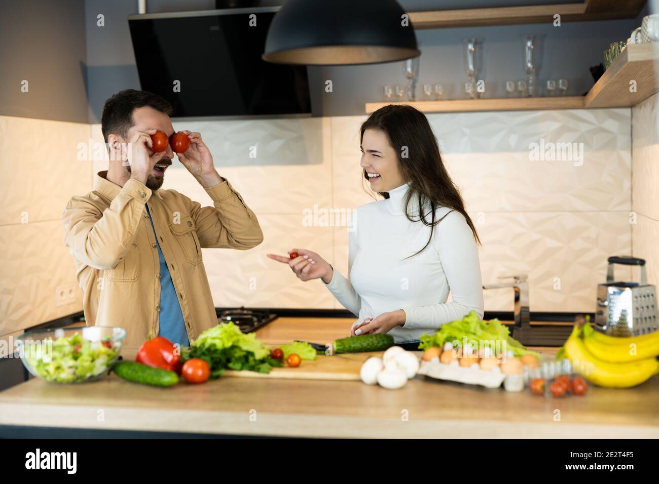 Cute couple are smiling and having fun in kitchen. Happy vegan people ...