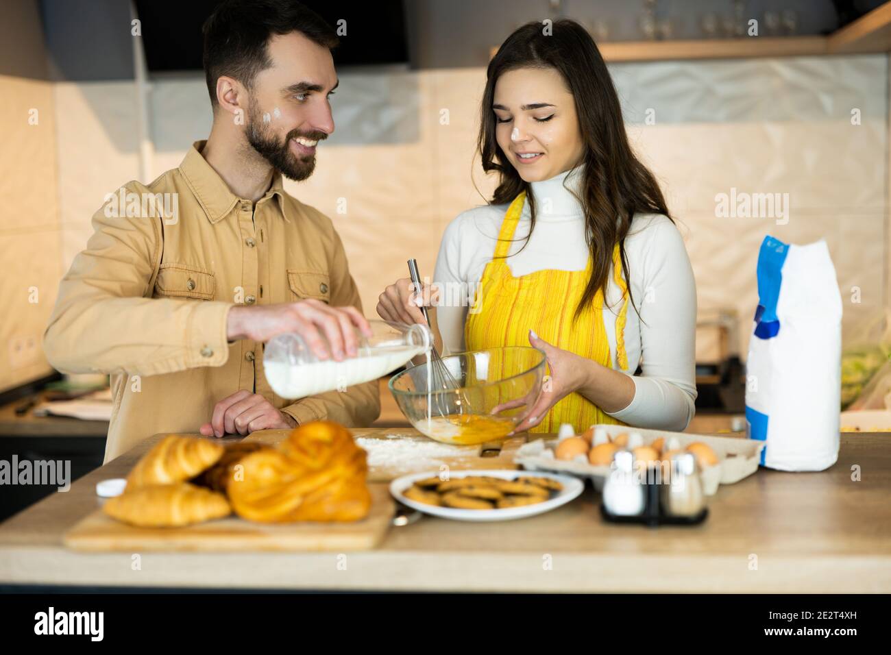 Couple are having fun while cooking and seem happy being together. Also ...