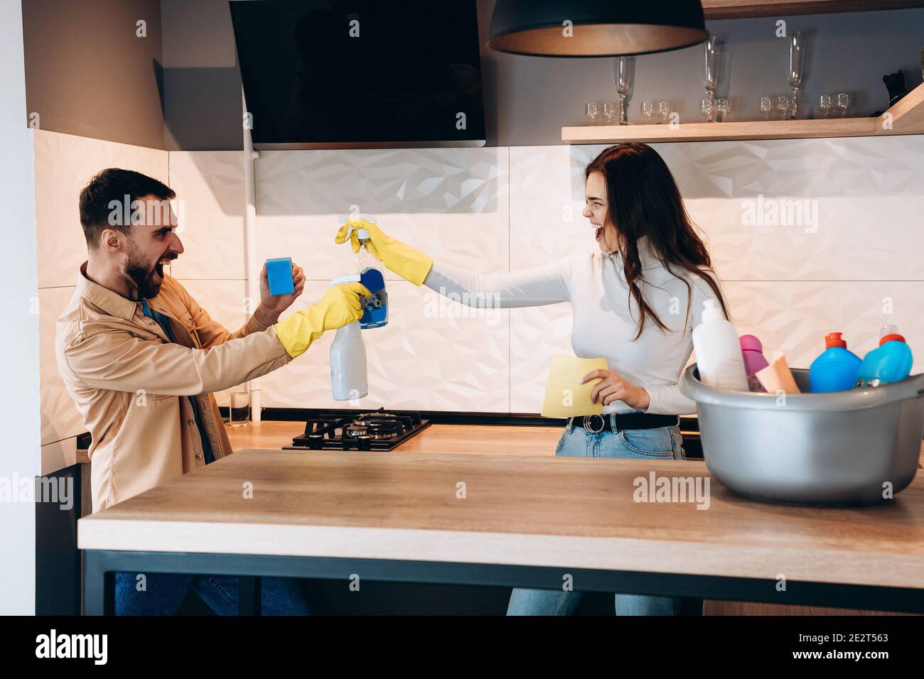 Pretty couple having fun and pretending fight with cleaning tools in ...