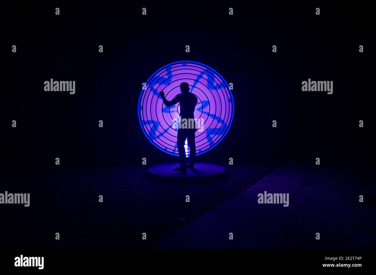 One person standing alone against beautiful color circle LED light ...