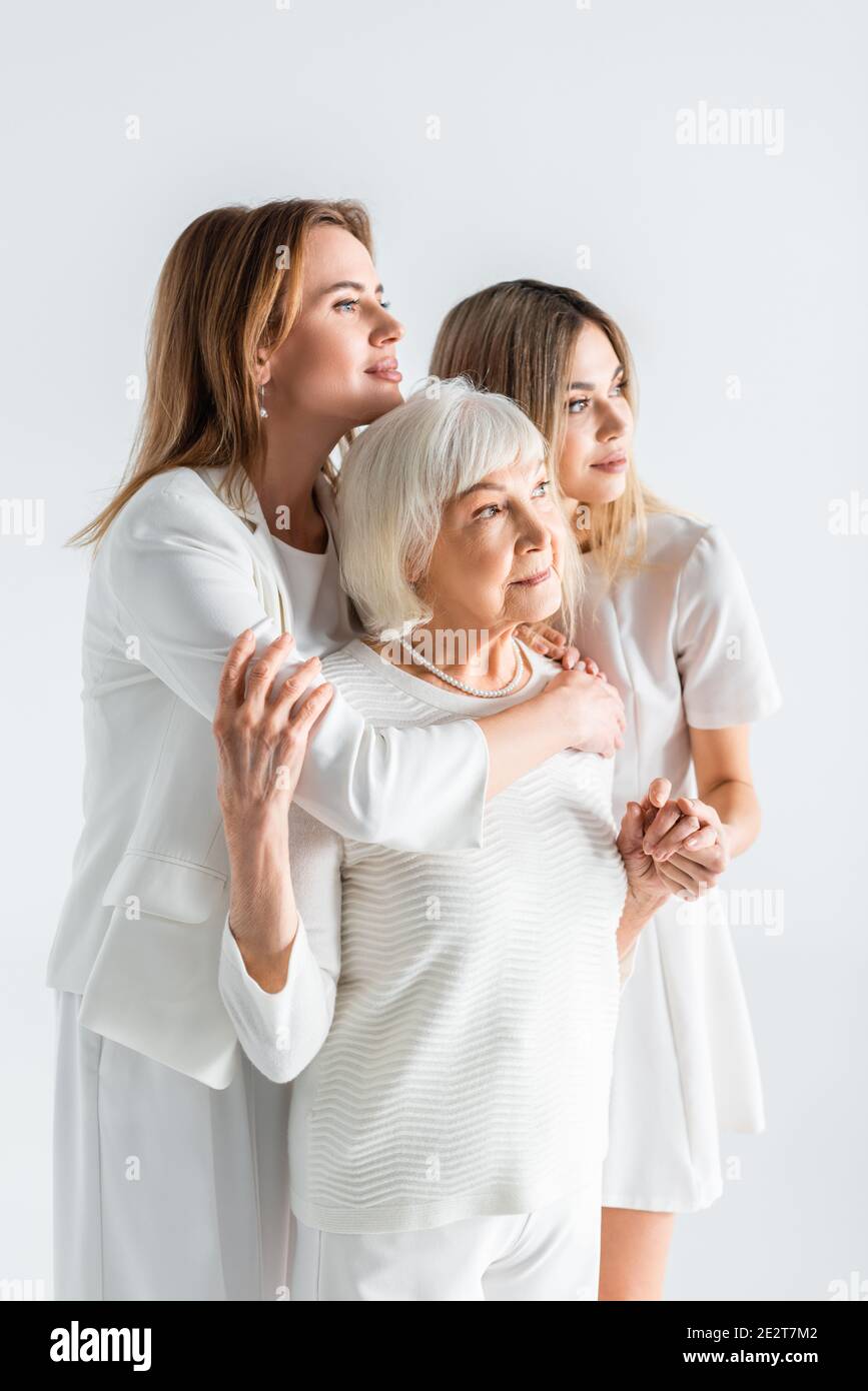 three generation of pleased women smiling while hugging isolated on ...