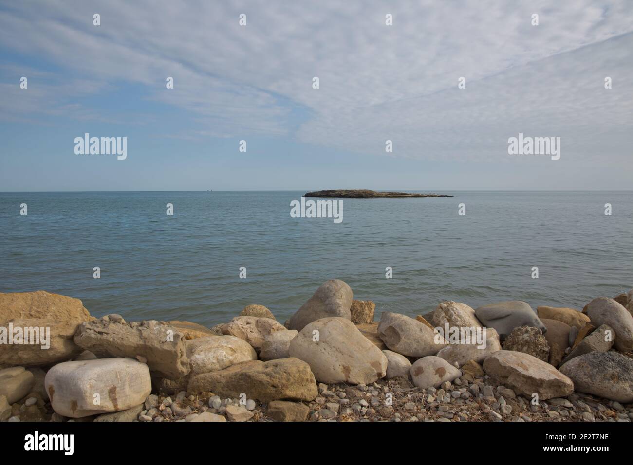 Caspian Sea clouds and a small island. Stones and blue sky by the sea ...