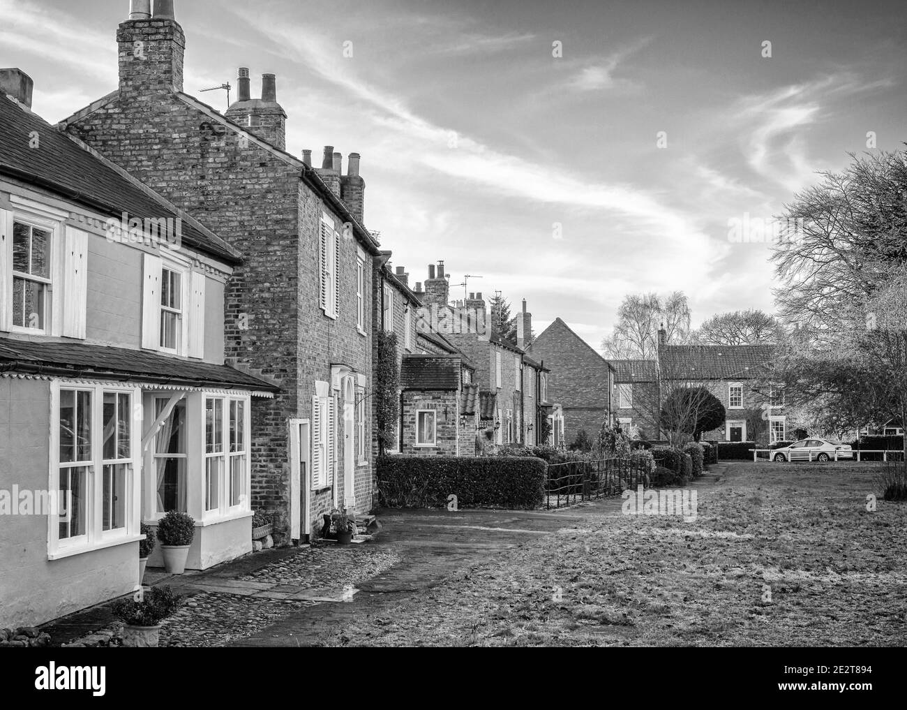 A row of cottages in a village setting. A trees catches the sunlight ...