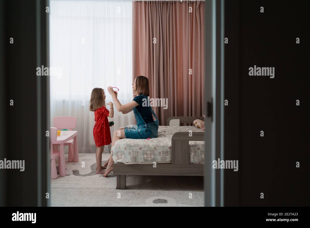 Happy delightful aunt wearing comfy jeans romper, spend time with her ...