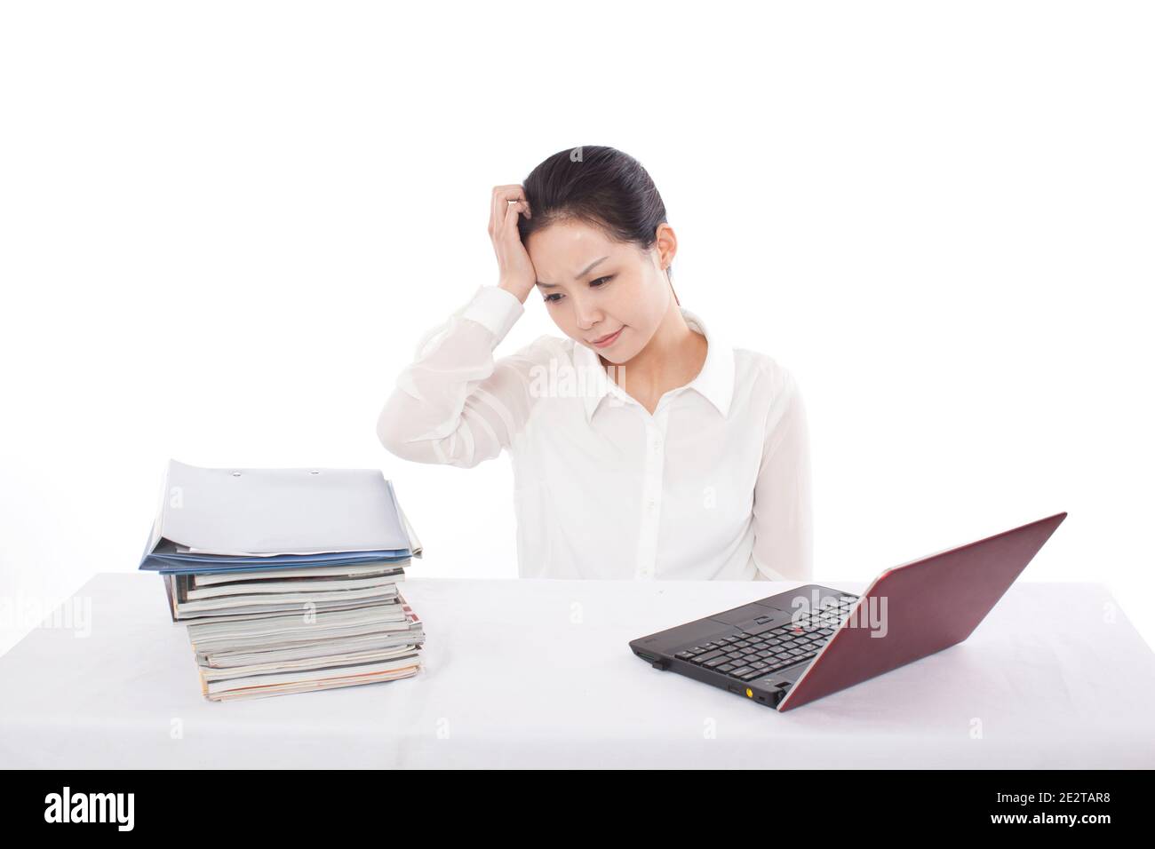 Young woman working in an office sitting at desk looking at files high ...