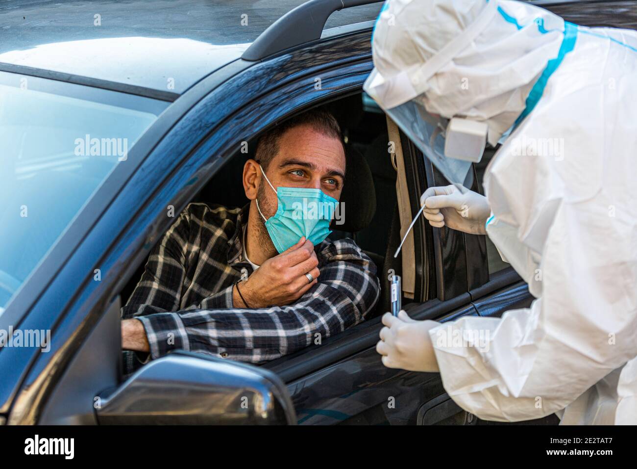 Man sitting in car, waiting for medical worker to perform drive-thru ...