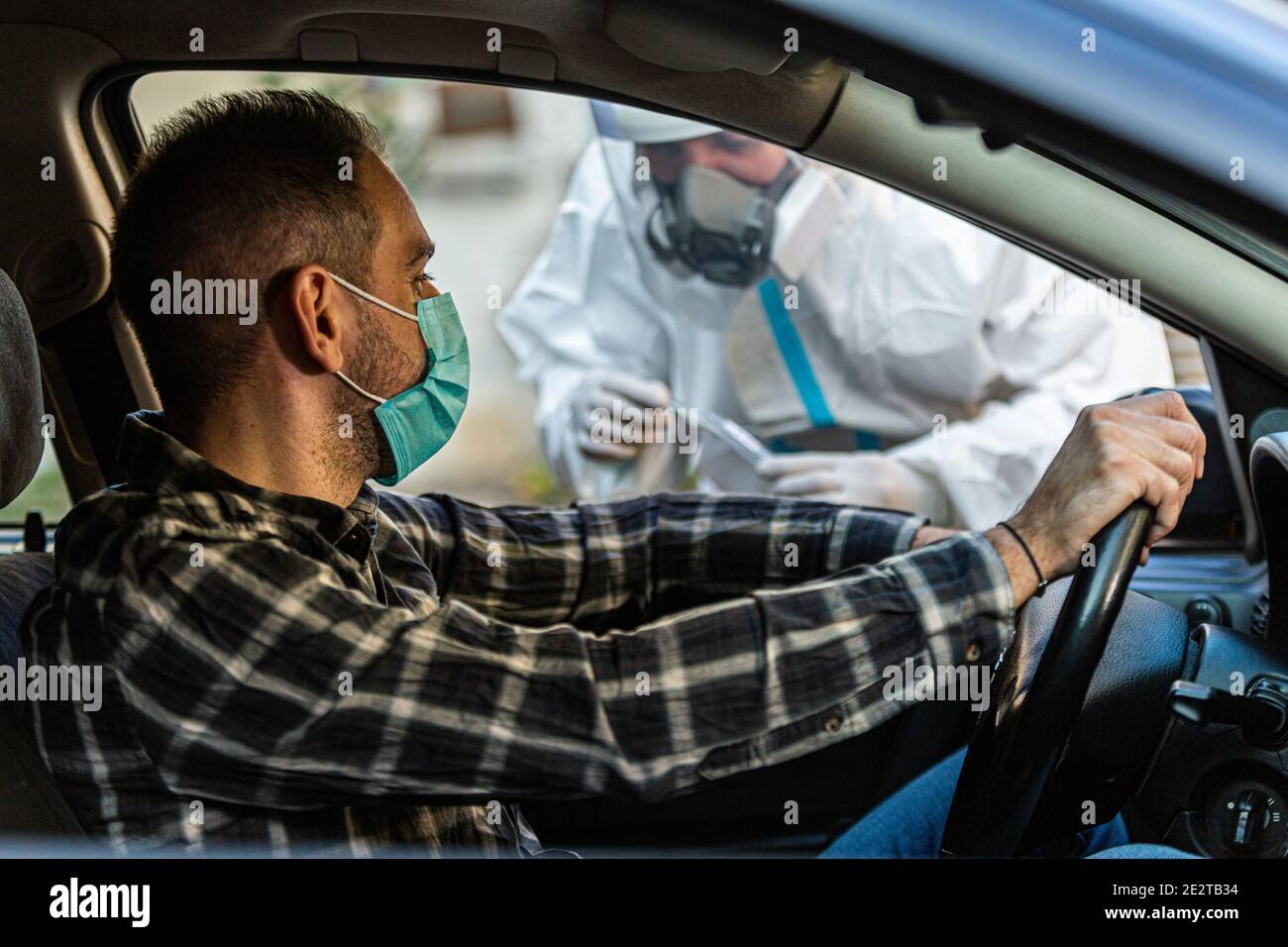 Man sitting in car, waiting for medical worker to perform drive-thru ...