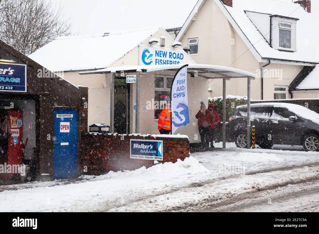 A queue of people standing outside a small fish and chip shop in ...