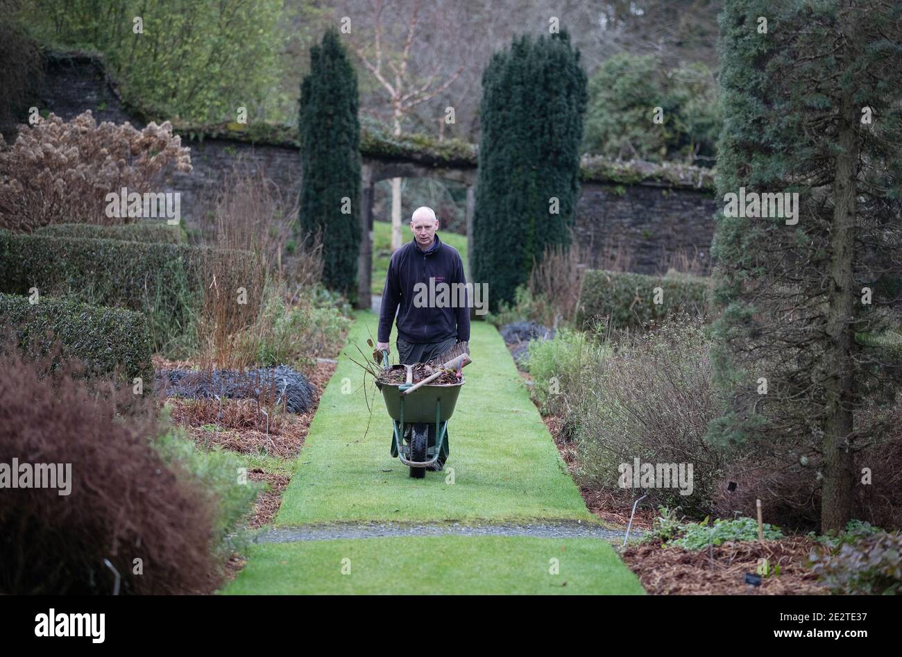 Head gardener Nick Howarth pushes a wheelbarrow through the walled ...