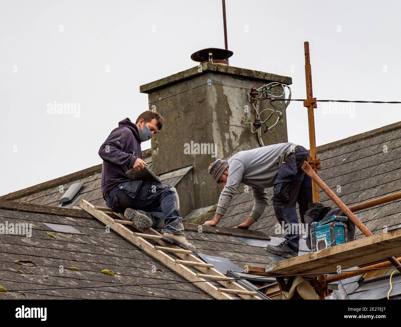 Builder working an roof wearing covid face mask Stock Photo - Alamy